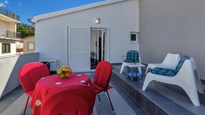 Terraço no telhado com mesa, cadeiras e um pequeno espaço para sentar.
