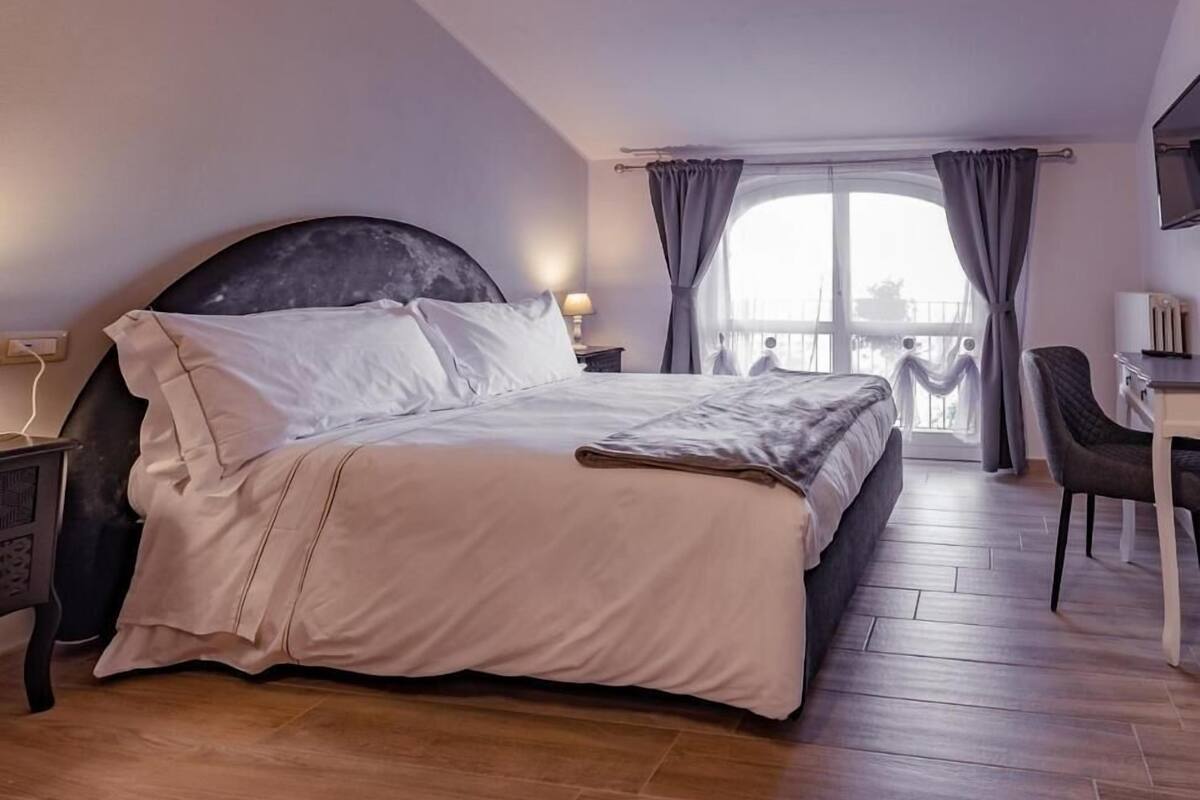 Quarto moderno com uma cama grande, uma escrivaninha e vista para o exterior.