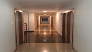 Um corredor longo e bem iluminado, com piso brilhante, que leva a uma porta no final.