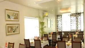Um restaurante com várias mesas, cadeiras e obras de arte emolduradas nas paredes.