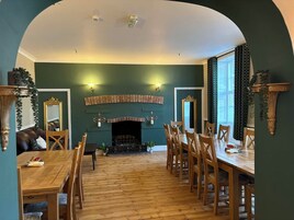 Uma sala de jantar com lareira, mobiliário de madeira e paredes verdes.