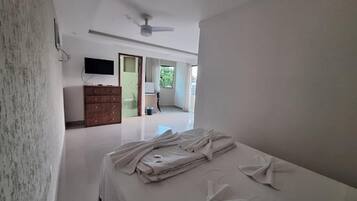 Quarto com cama, penteadeira, televisão e ventoinha no teto.