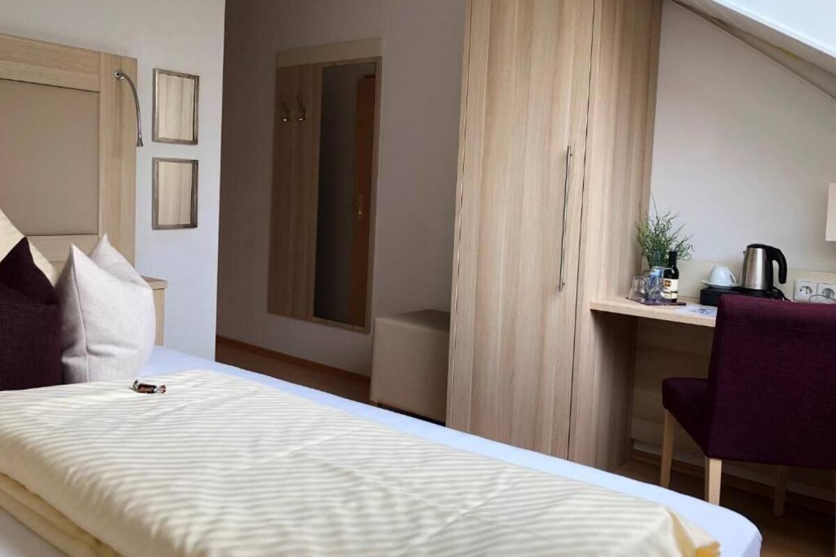 Quarto com cama, escrivaninha, cadeira e guarda-roupa.