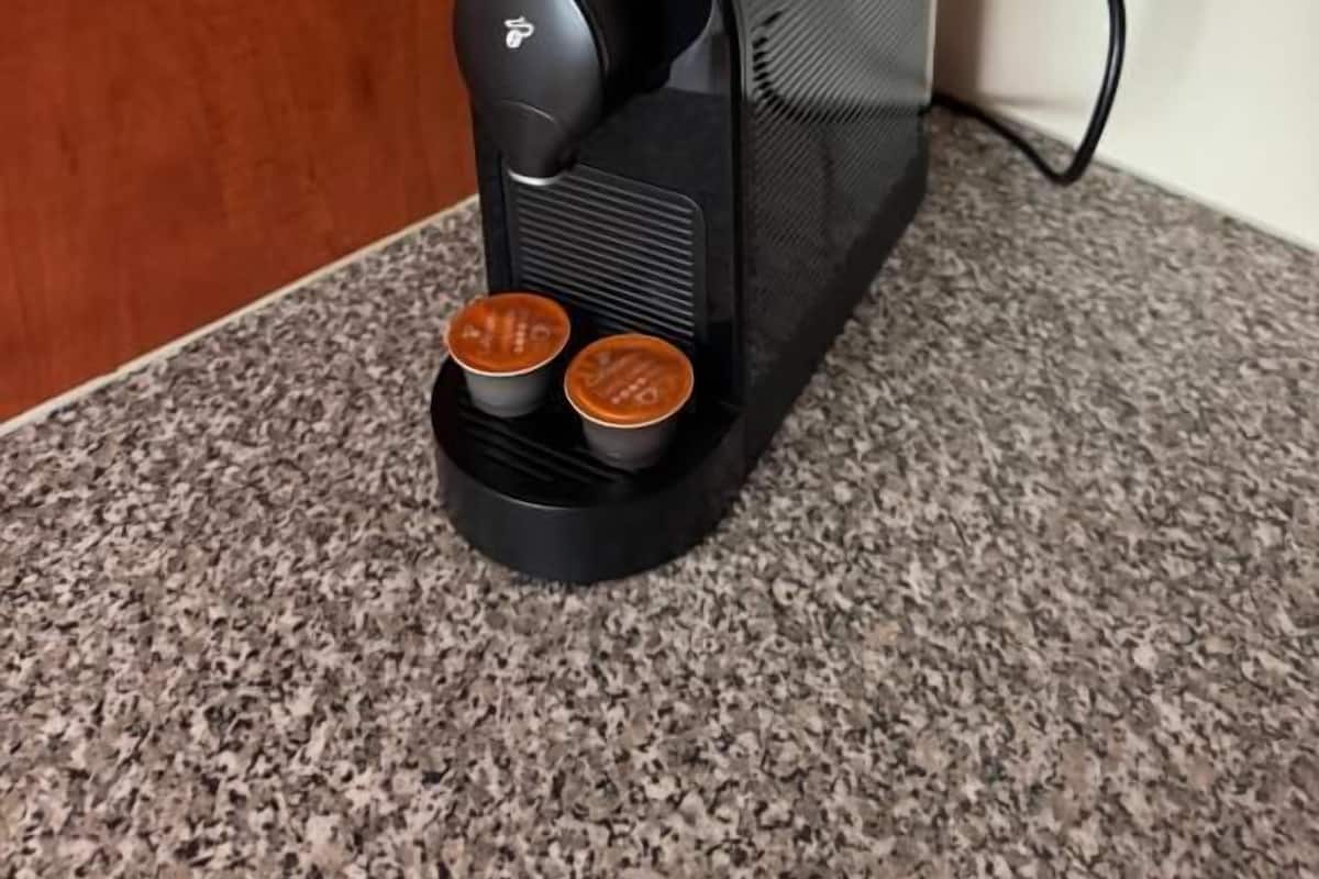 Uma cafeteira com duas cápsulas de café em uma bancada.