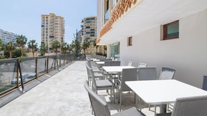 Terraço no telhado com área de estar externa, vista de edifícios altos e céu claro.