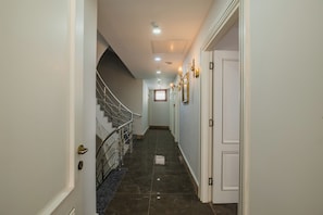 Um corredor com escada, porta e luminária.