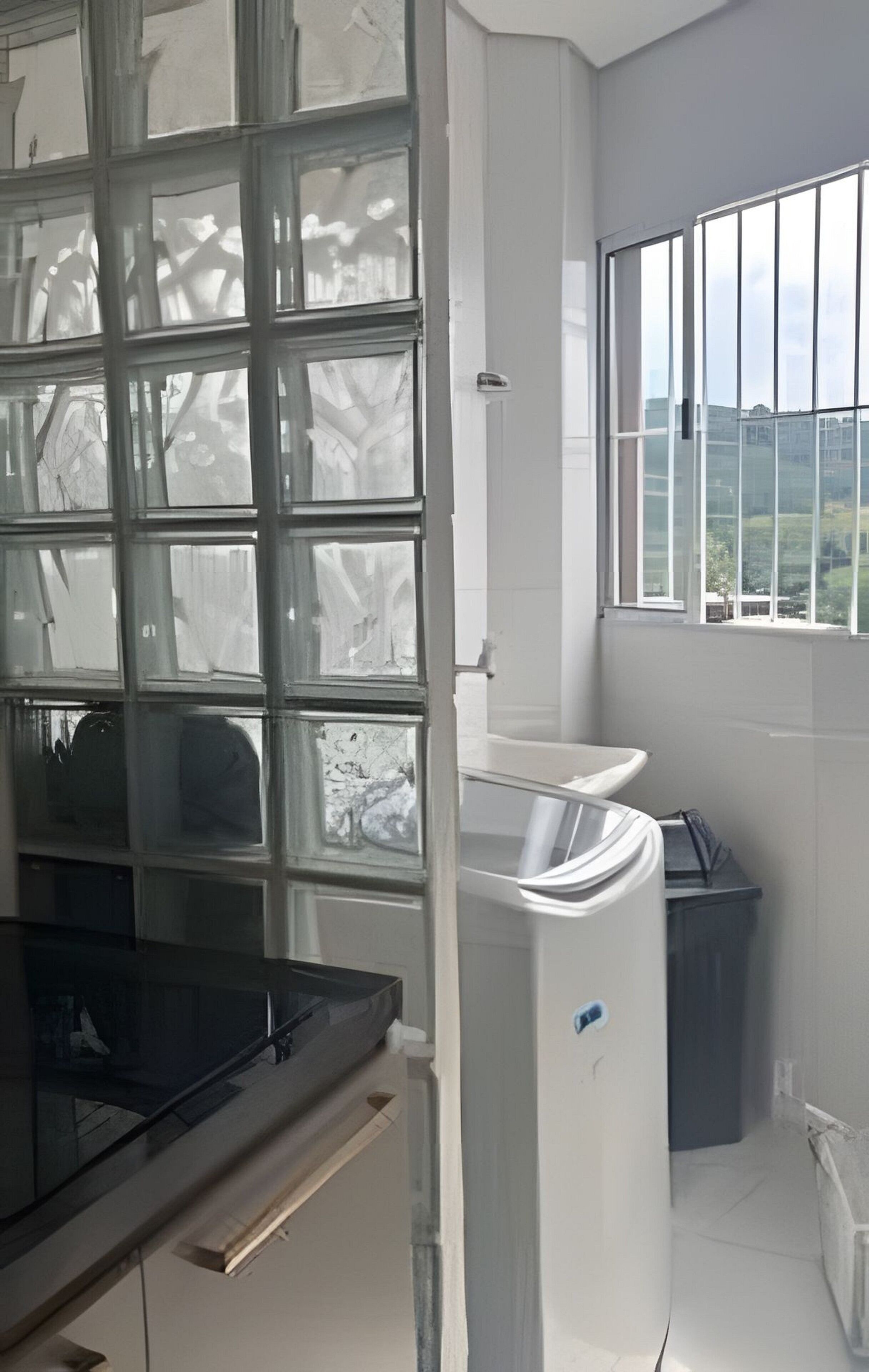 Uma cozinha com uma janela grande, uma geladeira branca e um balcão preto.
