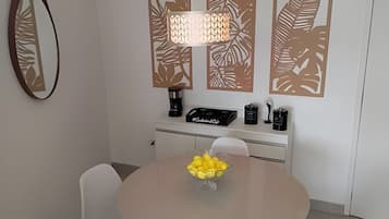 Uma sala de jantar com uma mesa redonda, cadeiras, máquina de café, chaleira e painéis decorativos na parede.
