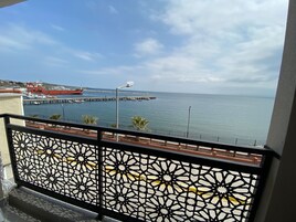Uma varanda com grade decorativa, vista para uma marina com barcos e um cais que se estende sobre a água.
