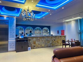 Uma área de bar com balcão de pedra, um candelabro e um espaço de estar com sofá de couro marrom.