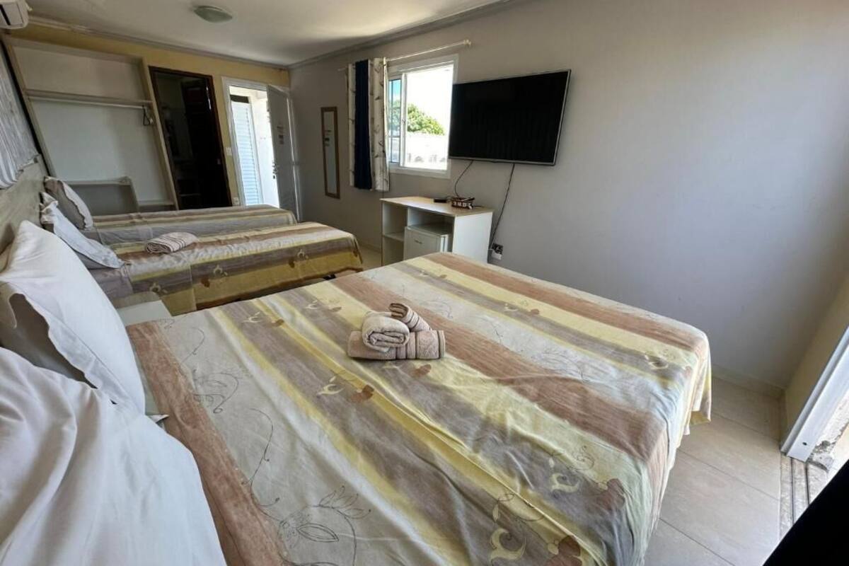 Quarto de hotel com duas camas, televisão, escrivaninha e janela.
