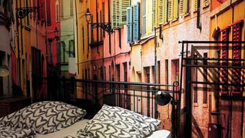 Cama com almofadas estampadas em quarto com mural de edifícios coloridos.