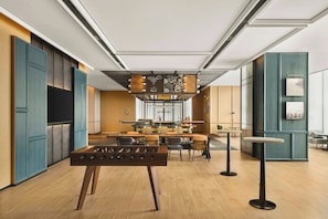 Decoração moderna com mesa de pebolim, área de bar e diferentes opções de assento.