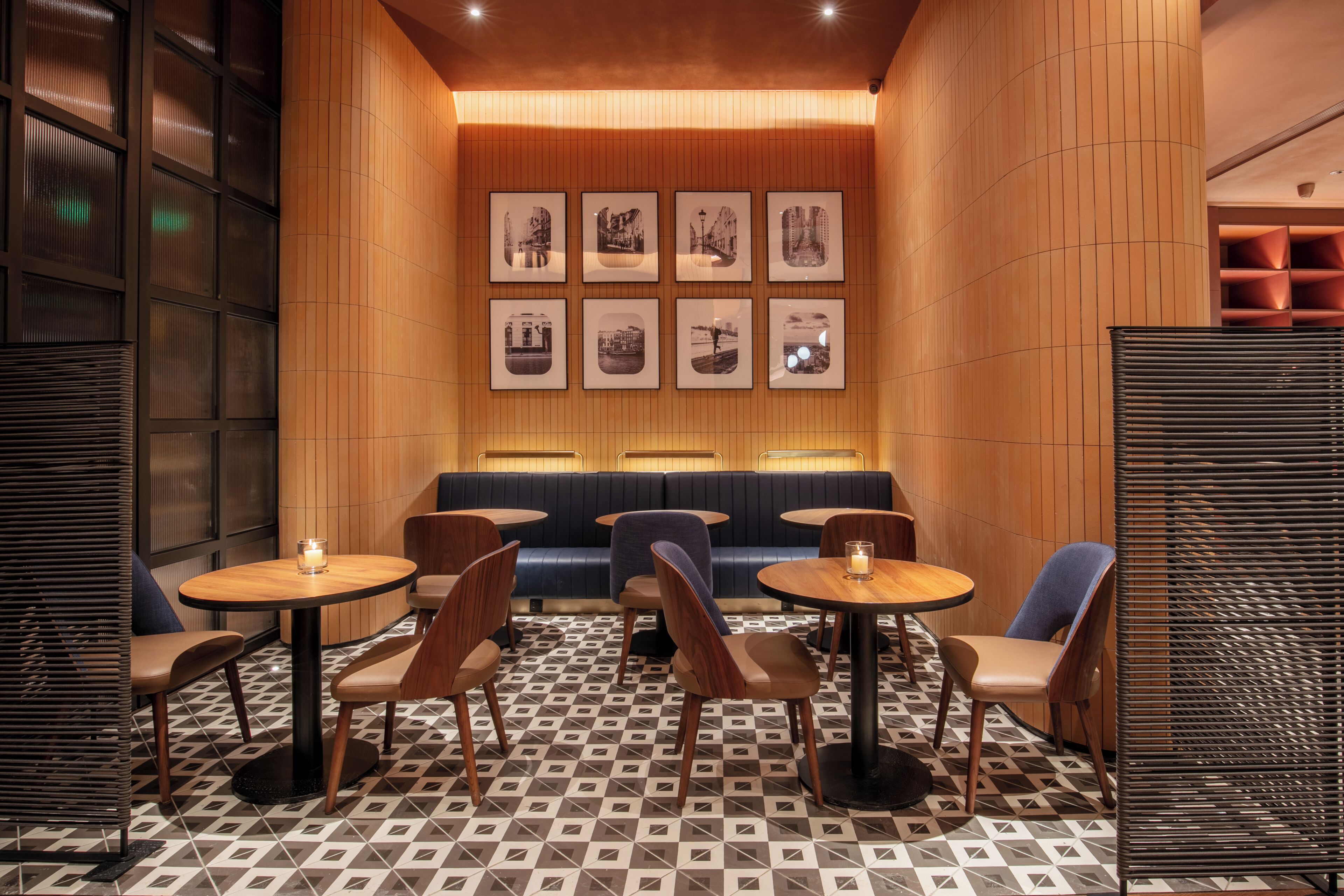 Interior de restaurante com paredes de painel de madeira, chão estampado e área de estar com mesas e cadeiras.