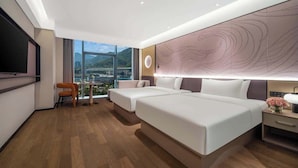 Quarto de hotel moderno com uma cama grande, uma mesa de trabalho, uma cadeira e uma televisão.