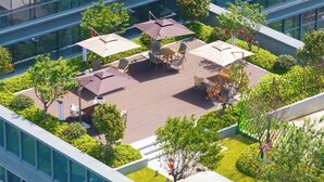 Um terraço ao ar livre com vários espaços de estar, rodeado por vegetação e arquitetura moderna.