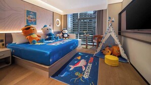Quarto de hotel moderno com uma cama, brinquedos macios, uma tenda e uma janela grande.