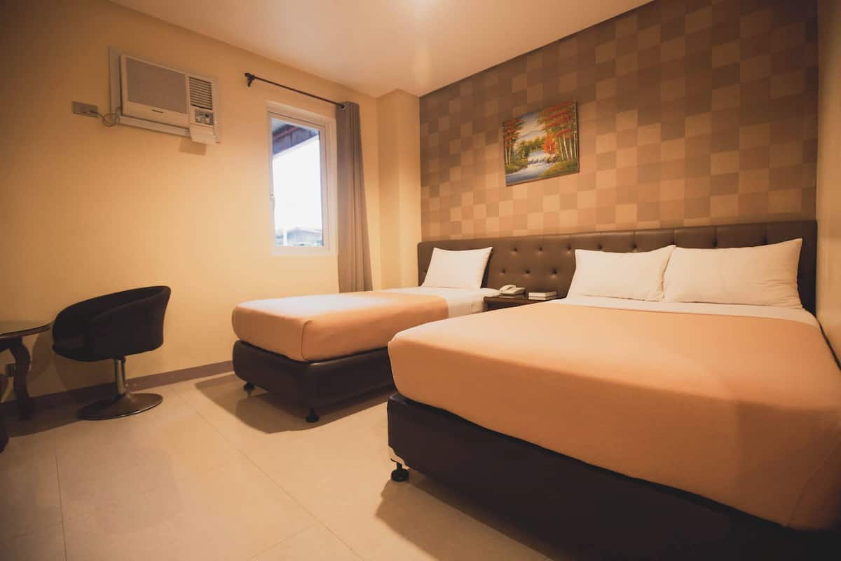 Quarto de hotel com duas camas, uma escrivaninha, uma cadeira, aparelho de ar condicionado e janela com cortinas.