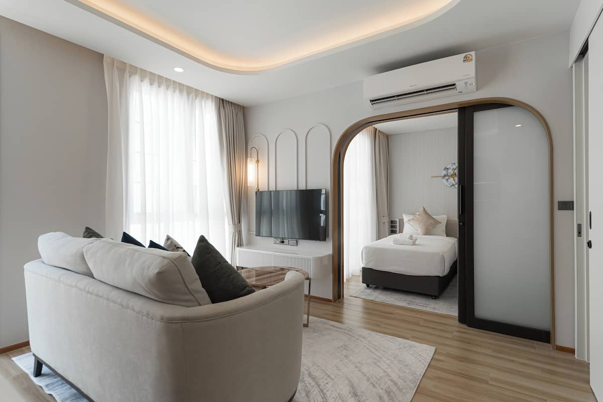 Quarto de hotel moderno com sofá, televisão, cama e ar condicionado.