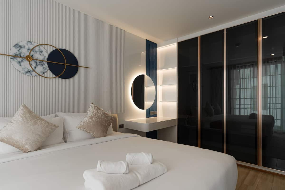Quarto moderno com uma cama grande, um espelho redondo e um guarda-roupa com portas deslizantes.