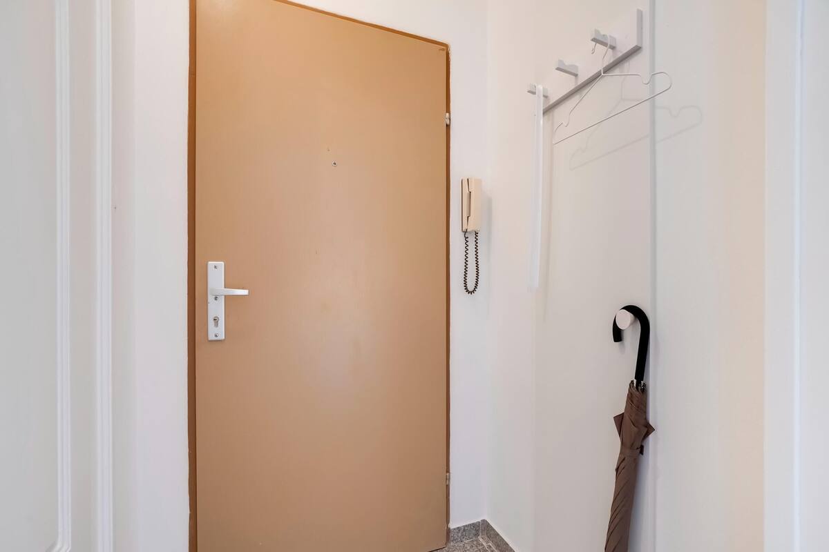 Porta fechada com um telefone e um guarda-chuva na parede.