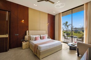 Quarto de hotel com uma cama grande, uma mesa de cabeceira, uma cadeira, uma mesa e vista para o exterior.
