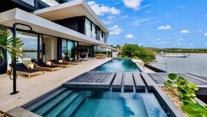 Uma casa moderna com piscina, área de estar externa e vista para a água.