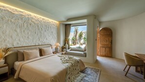 Quarto com cama grande, porta de madeira e vista para o exterior.