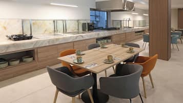 Uma cozinha moderna com bancada de mármore, forno embutido e área de jantar com mesa e cadeiras de madeira.