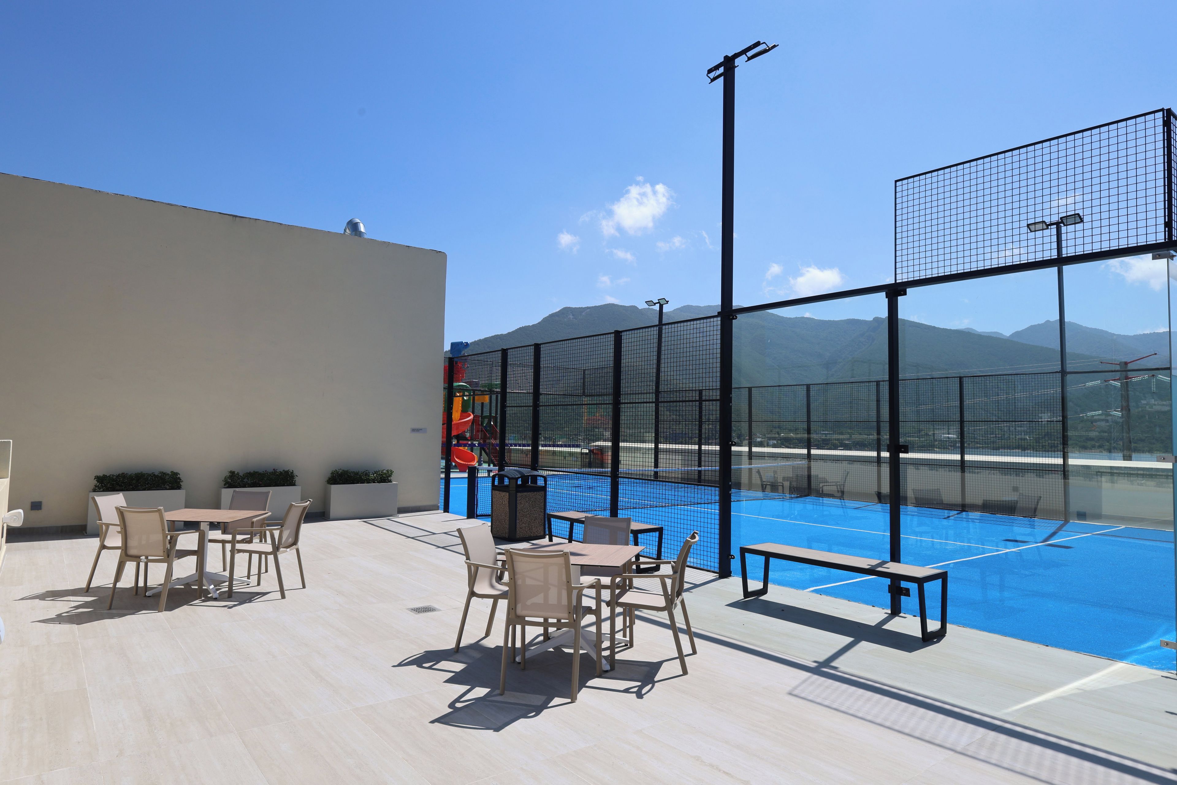 Área de piscina externa com assentos e vista para montanhas.