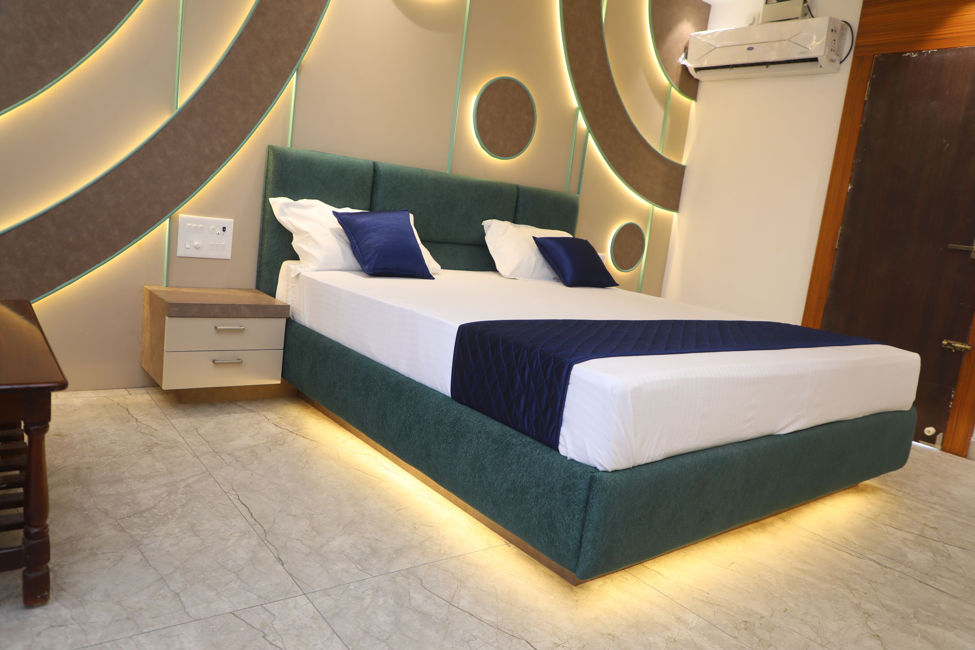 Quarto moderno com cama, mesas de cabeceira e ar condicionado fixado na parede.