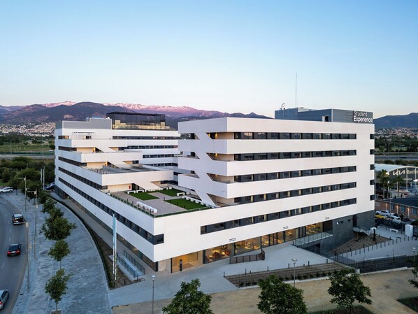 Um edifício moderno de vários andares com telhado plano, janelas amplas e fachada retilínea.