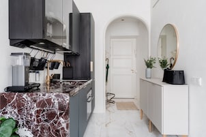 Uma cozinha moderna com bancada de mármore, armários pretos e coifa de aço inoxidável.