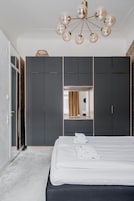 Quarto moderno com uma cama grande, guarda-roupa cinzento e um candelabro.