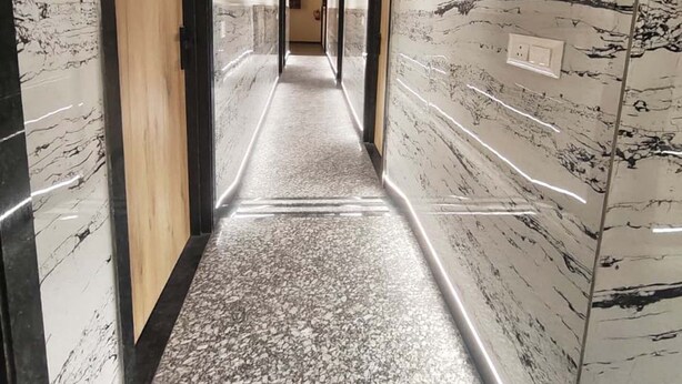Um corredor com paredes e pisos de mármore, portas em ambos os lados e balões pendurados no teto.