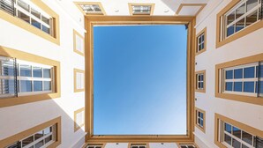 Visão através de um claraboia de um edifício com várias janelas e céu azul límpido.