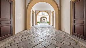 Um corredor com piso de pedra, portas de madeira e arcos.