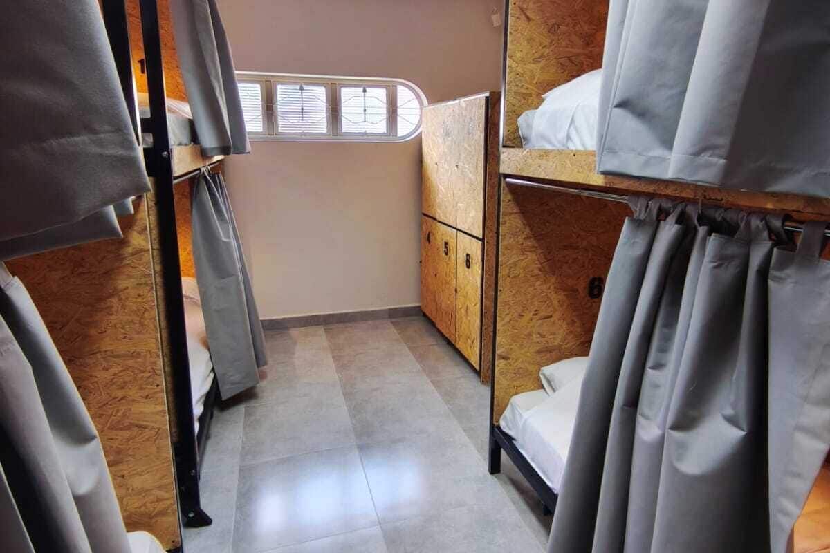 Quarto compacto com beliches, uma janela pequena e um armário de madeira.