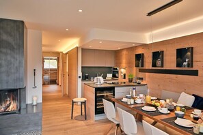 Uma cozinha moderna com ilha central, armários de madeira e um espaço de refeições com mesa posta para o café da manhã.