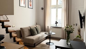 Uma sala de estar moderna com sofá, mesa de centro, mesa de jantar com cadeiras, um arranhador para gato e uma janela com cortinas.