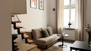 Uma sala de estar moderna com um sofá, uma mesa de centro, uma mesa de jantar e uma escada que leva a um andar superior.