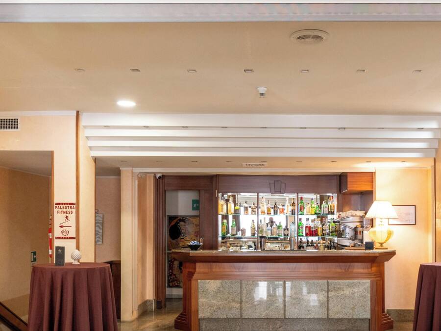 Uma área de bar com balcão, um letreiro para 'Palestra Fitness' e uma luminária à direita.