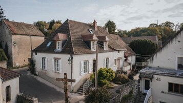 Um edifício de estilo europeu tradicional, com telhado inclinado e uma escadaria aparente, situado numa rua estreita.
