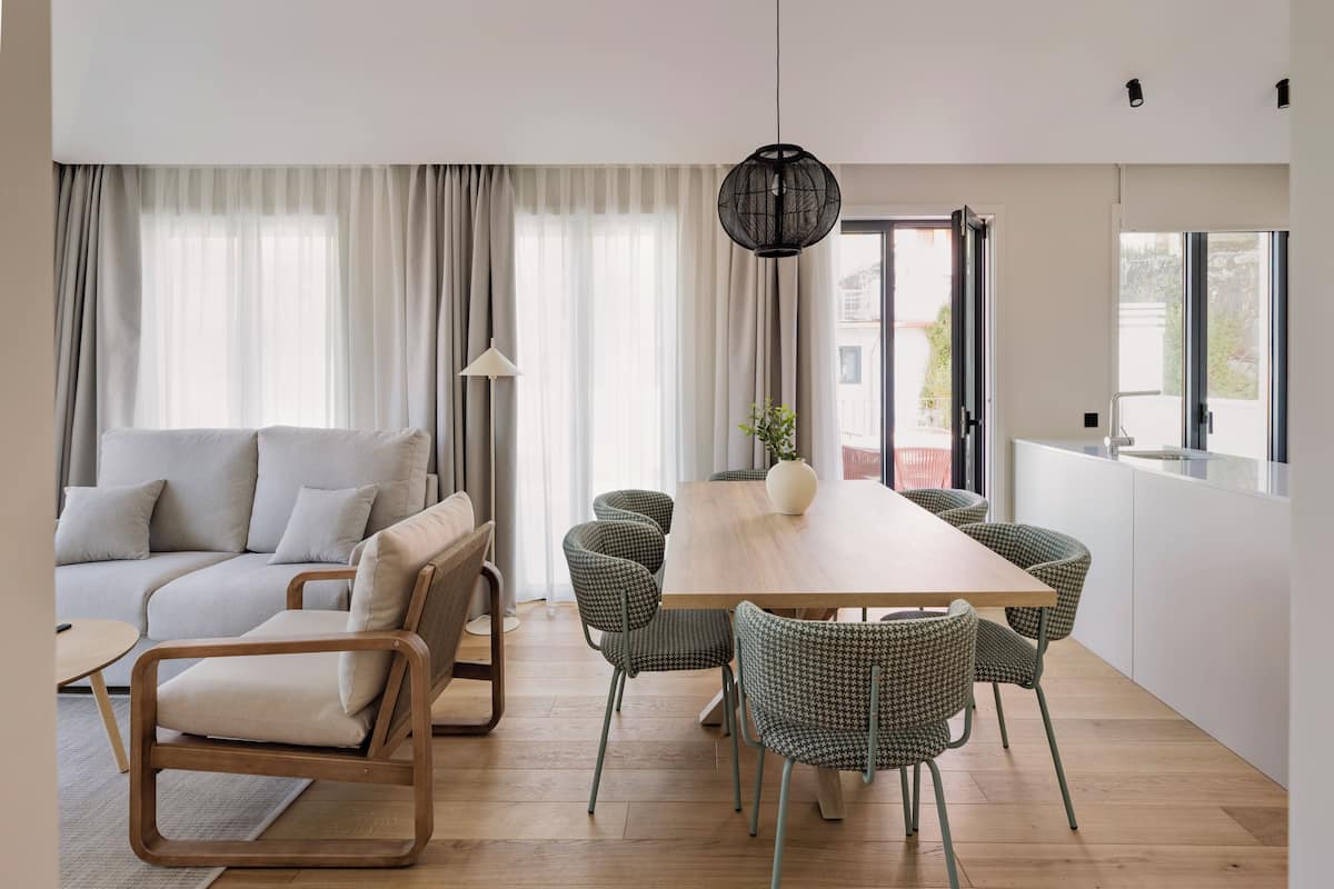 Uma sala de estar moderna com sofá, mesa de jantar, cadeiras e luminária pendente.