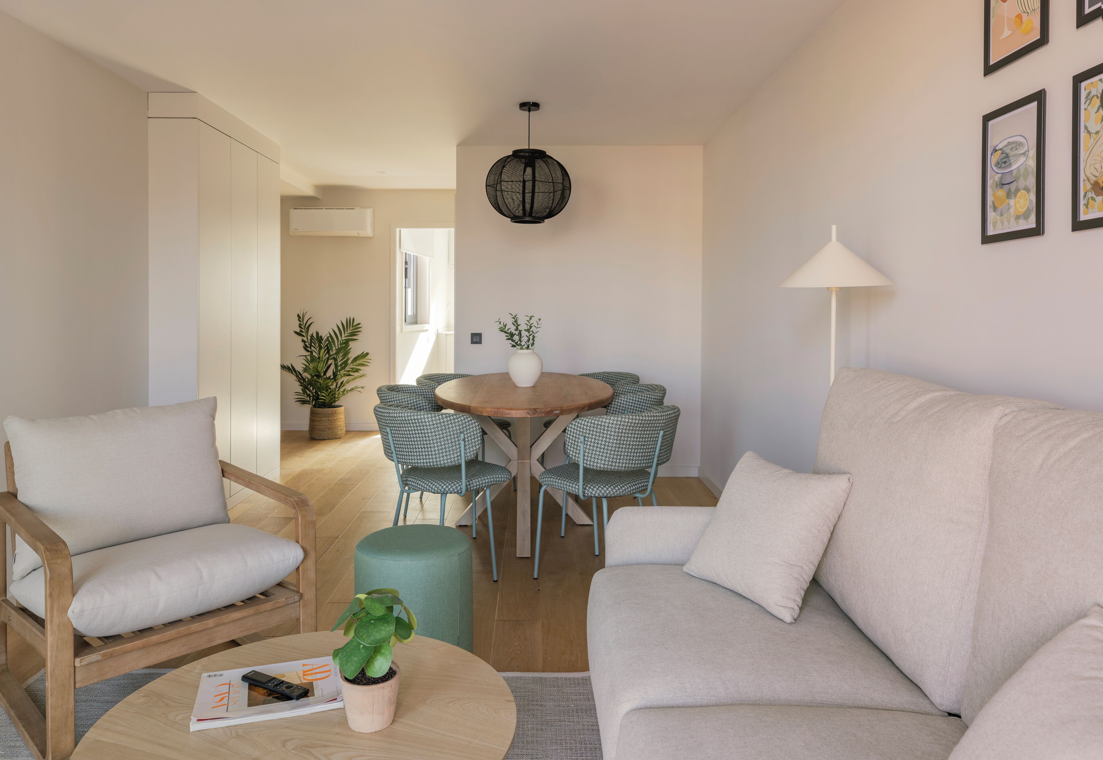 Uma sala de estar moderna com sofá, poltrona, mesa redonda e cadeiras.