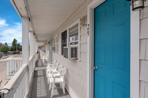 Um edifício com porta azul, número 29, e uma fileira de cadeiras brancas no alpendre.