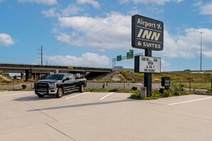 Placa do Inn & Suites Airport, um estacionamento e um caminhão.