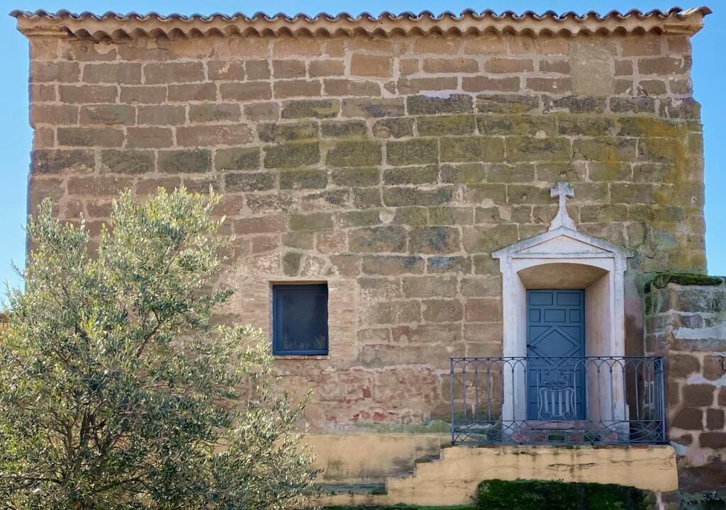 Um edifício de pedra com uma pequena varanda e uma porta.