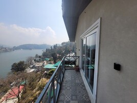 Varanda com vista para um corpo de água e colinas ao longe.