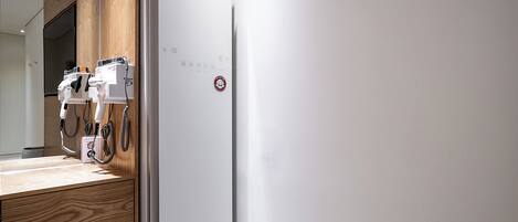 Cozinha moderna com frigorífico embutido, bancada de madeira e máquina de café montada na parede.